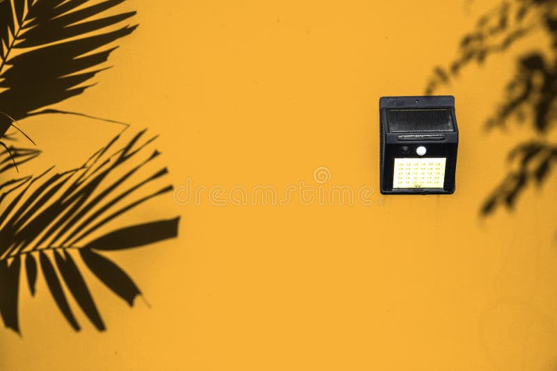 Solar-powered Motion Sensor Light Isolated on Yellow Cement or Concrete ...