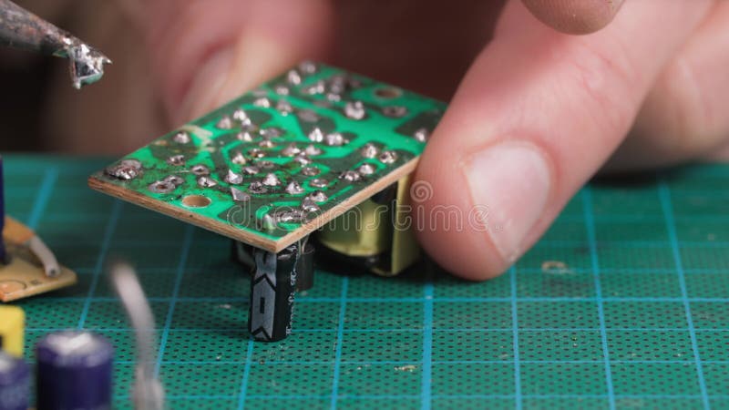 Soldering Man Using a Soldering Iron Repairs a Microcircuit on Table ...