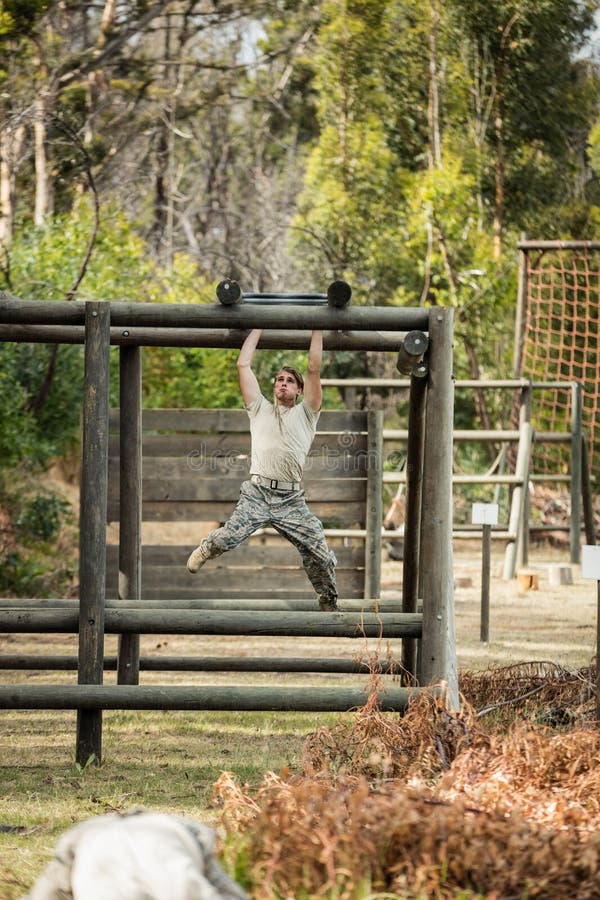 Male Soldier Swinging from Log Above Beams in Forest Obstacle Course ...