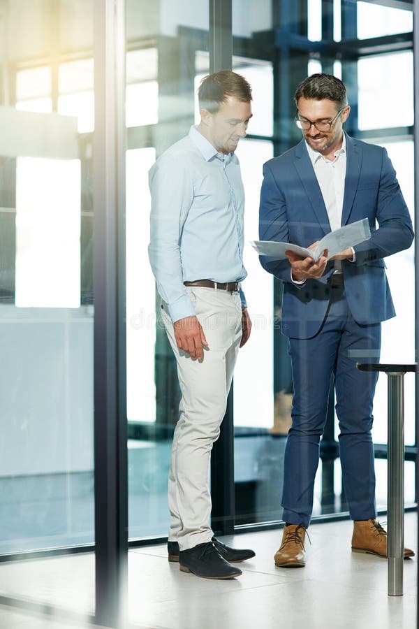 Solving Problems As a Team. Two Businessmen Talking Over Some Paperwork ...