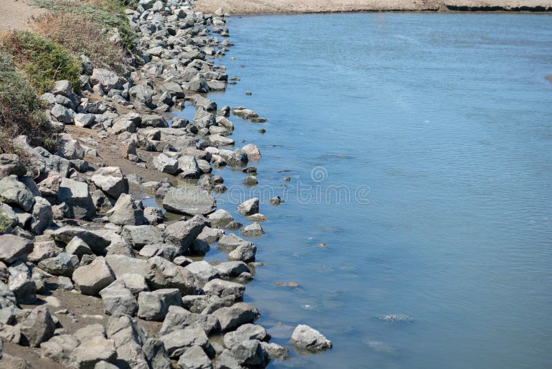 Rocks Lining the Edge of a Coast Sandline with a Clear Sky and R Stock ...
