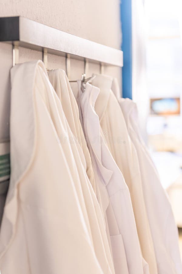 Some White Labcoats Hanging on a Coat Rack Agains the Wall of a ...