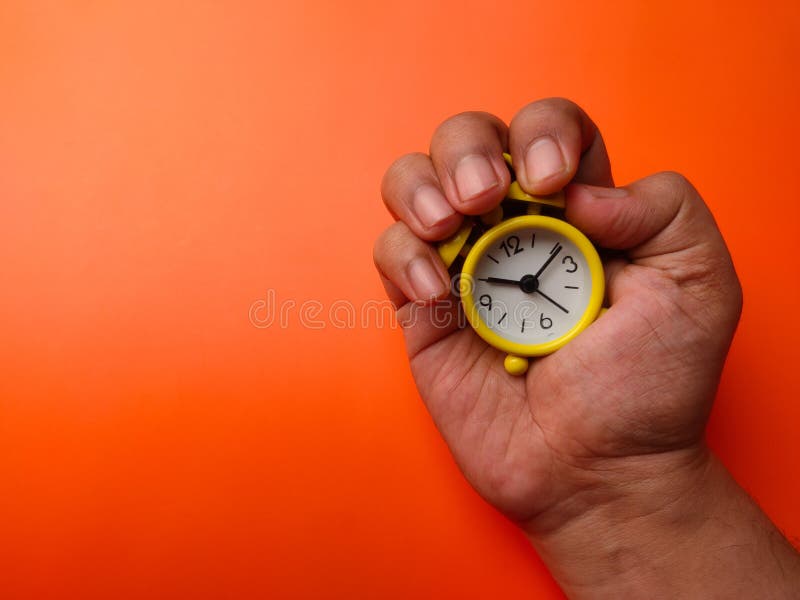 Someone Hand Holding Yellow Alarm Clock on a Orange Background Stock ...