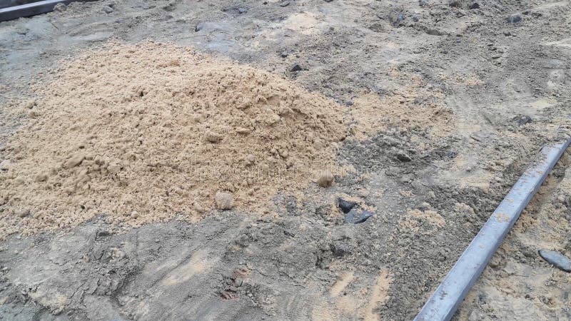 Someone is Throwing a Pile of Yellow Sand on a Gray Construction Site ...
