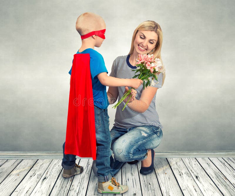 The Son In The Costume Of A Superhero Gives His Mother A Bouquet Of