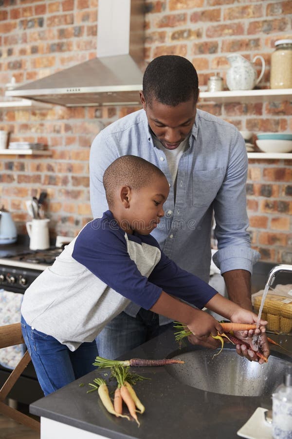 Son Helping Father To Prepare Vegetables for Meal in Kitchen Stock ...