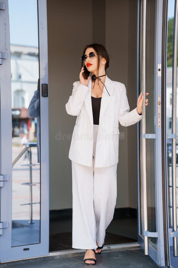 Sophisticated Woman in Striped Suit Exiting Modern Building with ...