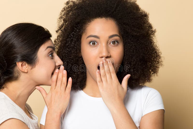Sorpresa Ragazza Afro Americana Che Ascolta Il Segreto Di Un Amico Indiano Immagine Stock