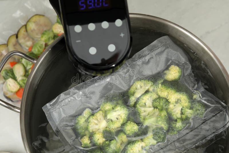 Sous Vide Cooker and Vacuum Packed Broccoli in Pot on White Table ...