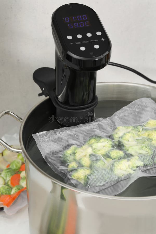 Sous Vide Cooker and Vacuum Packed Broccoli in Pot on White Table ...