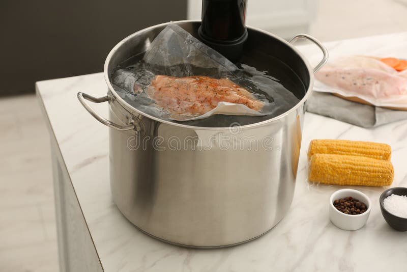 Sous Vide Cooker and Vacuum Packed Meat in Pot on White Marble Table ...