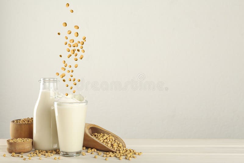 Soy Beans Falling into Glass of Plant Milk on White Table. Space for ...