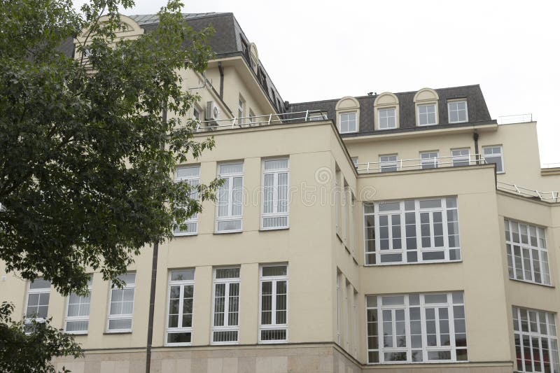 A Spacious Building with Many Windows and a Tree in Front Stock Photo ...