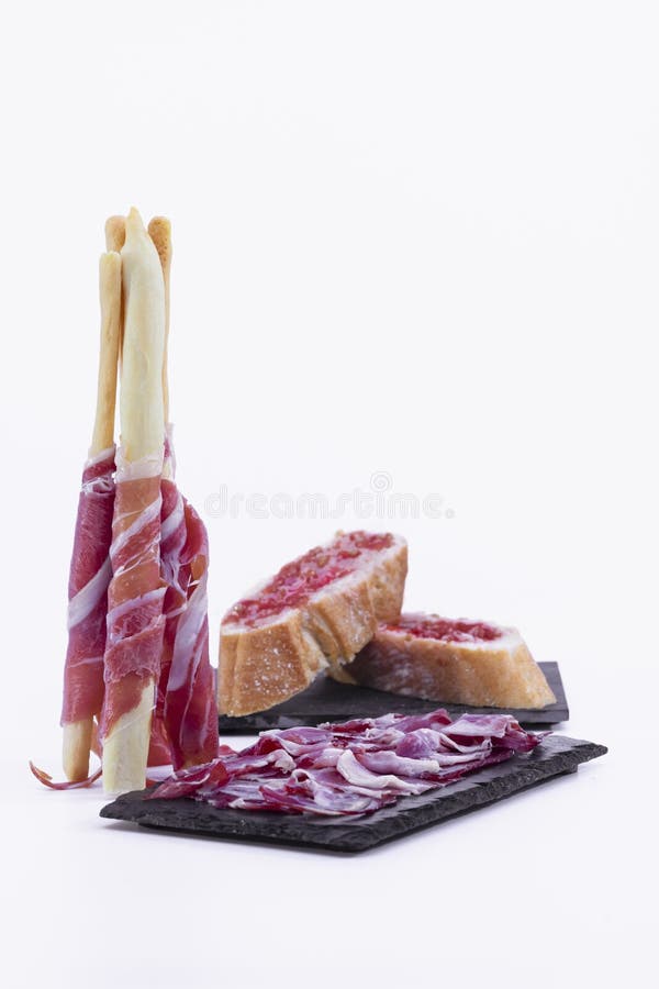 Spanish Ham on a Dark Plate Surrounded by Bread-sticks Wrapped in Ham ...