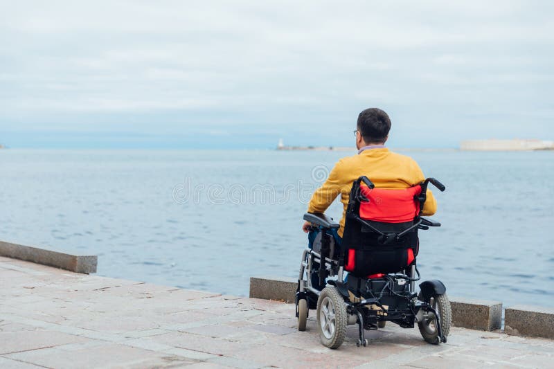 A Special Person with Disabilities by the Sea on a Walk Looks at the ...