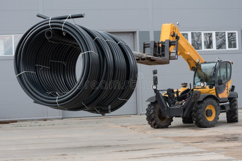 A Special Tractor is Engaged in Loading and Moving Pipes. Plastic Pipes ...