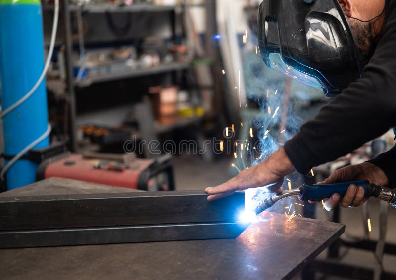 Performing a Weld: the Man in the Welding Mask is Positioned with the ...