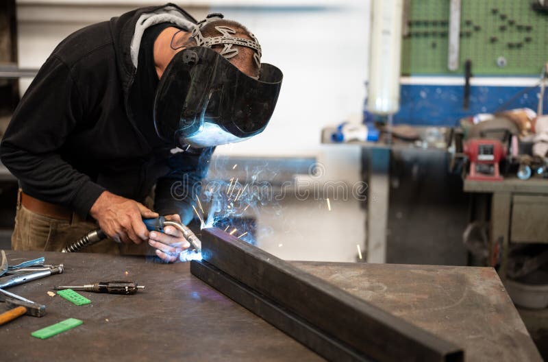Performing a Weld: the Man in the Welding Mask is Positioned with the ...