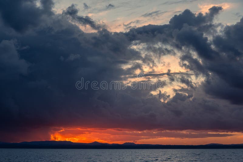Spectacular Sunset Above a Lake in the Middle of Heavy, Moody Clouds ...