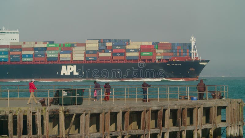 Spectators on a Pier Watch a Large Cargo Ship Approaching the Golden ...
