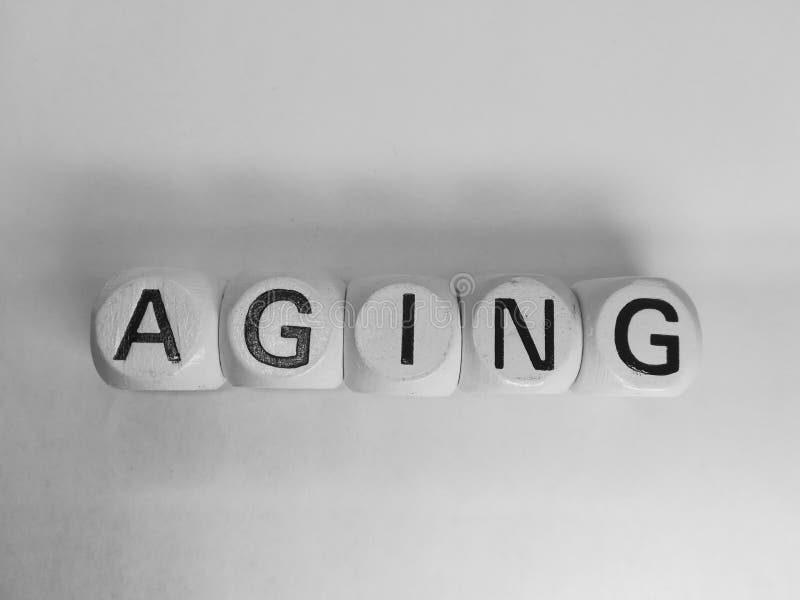 The Word AGING is Written on White Paper on a Wooden Background Near a ...