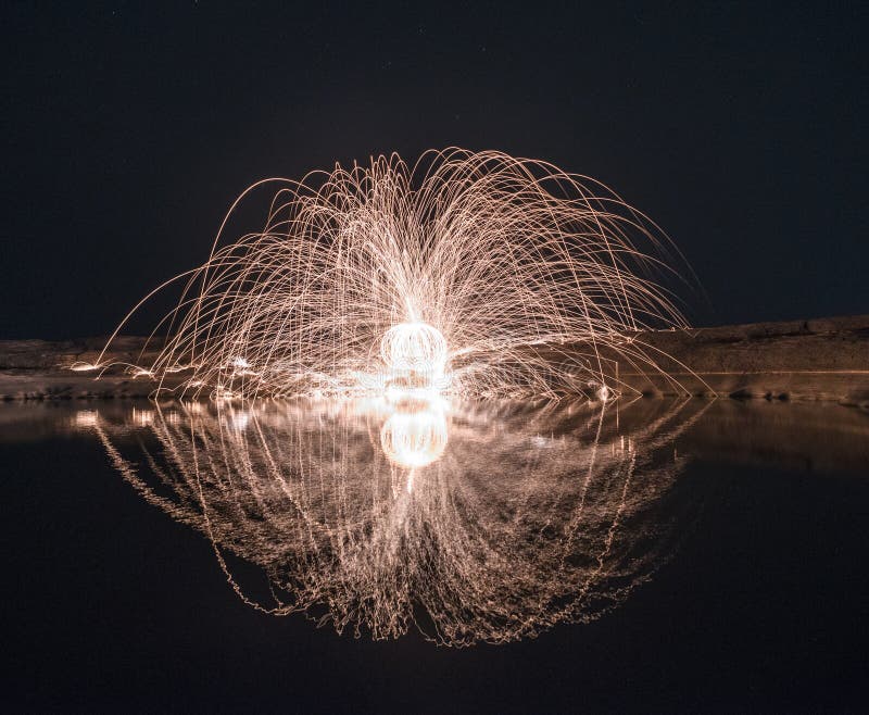 Spinning Fire with the Blue Sky and Water Reflection Stock Photo ...