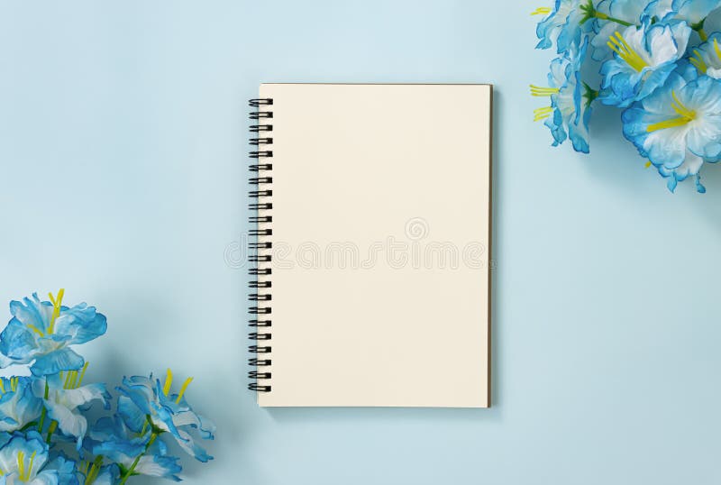 Spiral Notebook and Blue Flowers at Bottom Left and Top Right Corner on ...