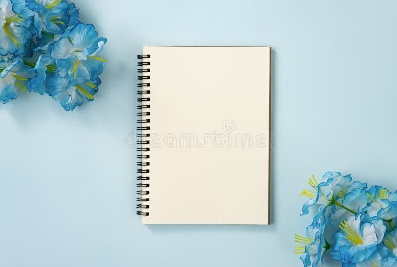 Spiral Notebook and Blue Flowers at Bottom Right and Top Left Corner on ...
