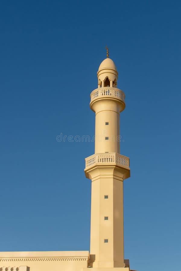 A Spire and Minaret of a White and Orange Mosque with a Blue Sky ...