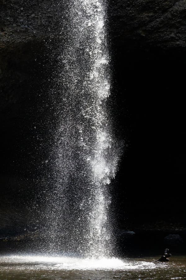 Splashing Waterfall with Bright Sunlight Drop on Pond with Dark Cave ...