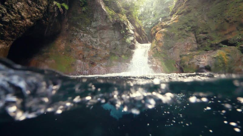 Split View Half Over and Under a Waterfall, with Water Foams and ...