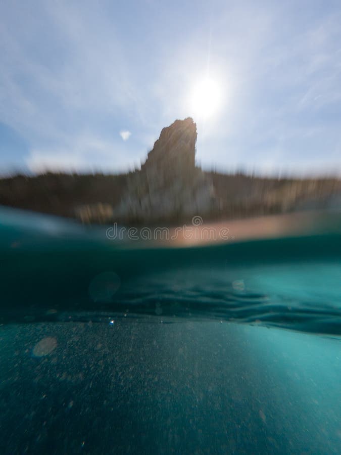 Split View of Rock Raising from Sea and Water Underneath. Stock Photo ...