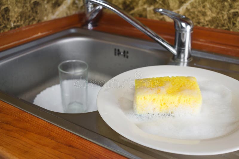 Sponge with Foam for Washing Dishes on White Plate at the Kitchen ...
