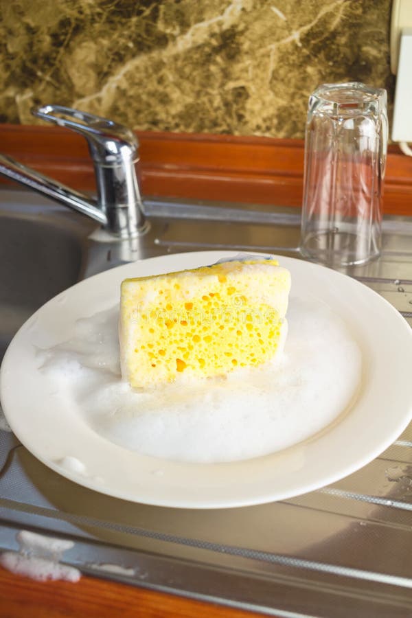 Sponge with Foam for Washing Dishes on White Plate at the Kitchen ...