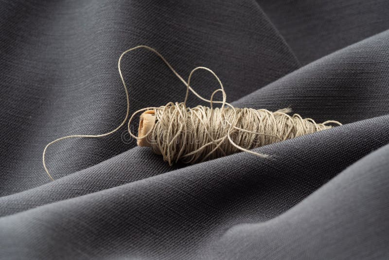 A Spool with Beige Threads in a Draped Soft Gray Fabric, Close-up ...