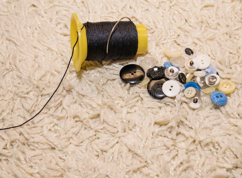 A Spool of Black Strong Thread and a Bunch of Buttons Lie on a White ...