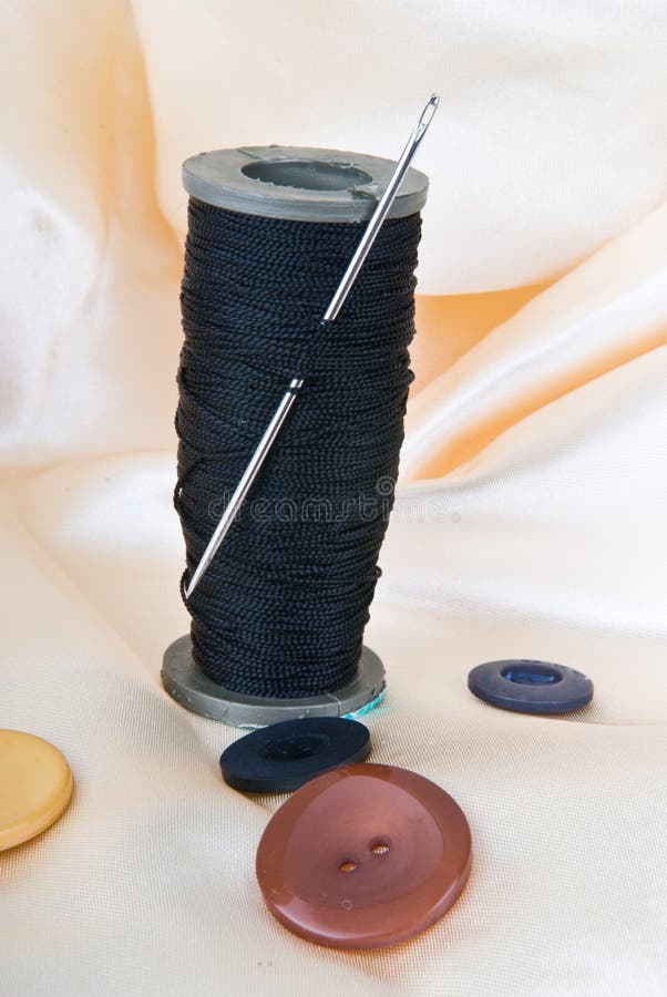 Spool of Black Thread with a Needle and Buttons Stock Photo - Image of ...