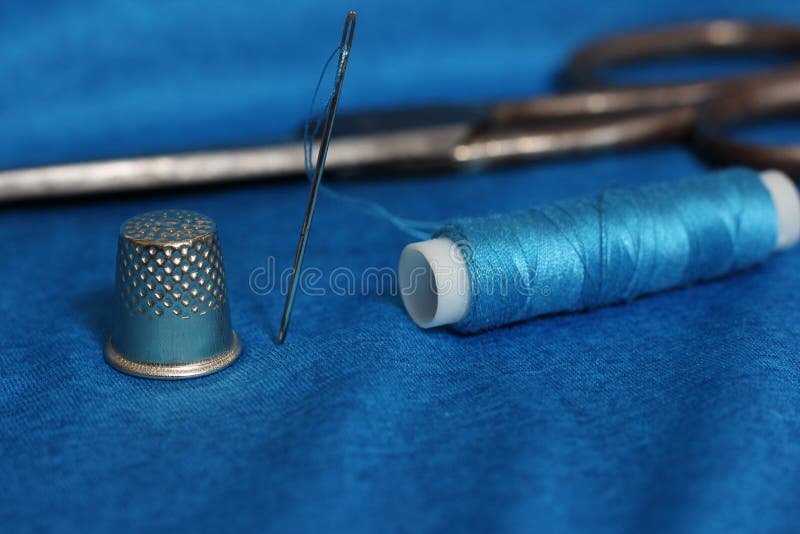 Spool of Blue Thread, Thimble and Needle on Blue Fabric Stock Image ...