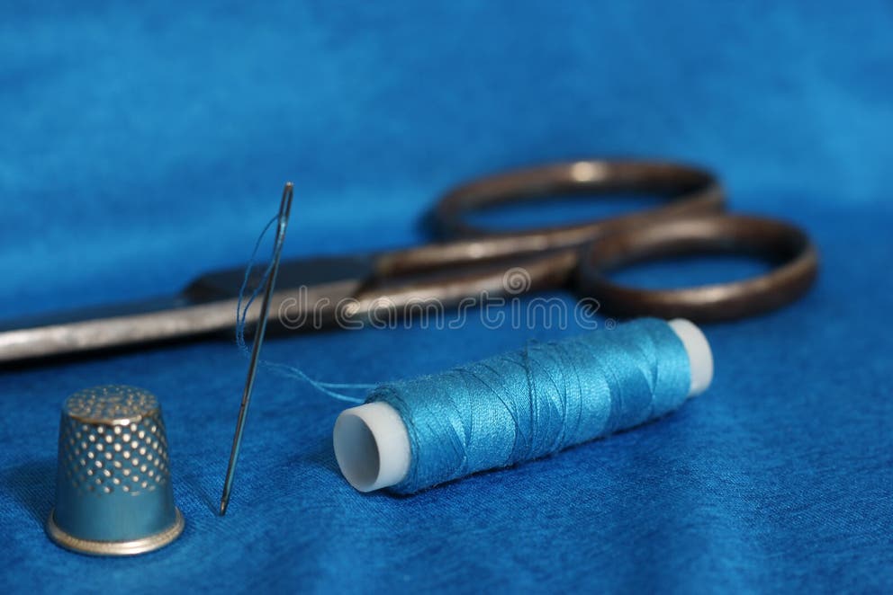 Spool of Blue Thread, Thimble and Needle on Blue Fabric Stock Image ...