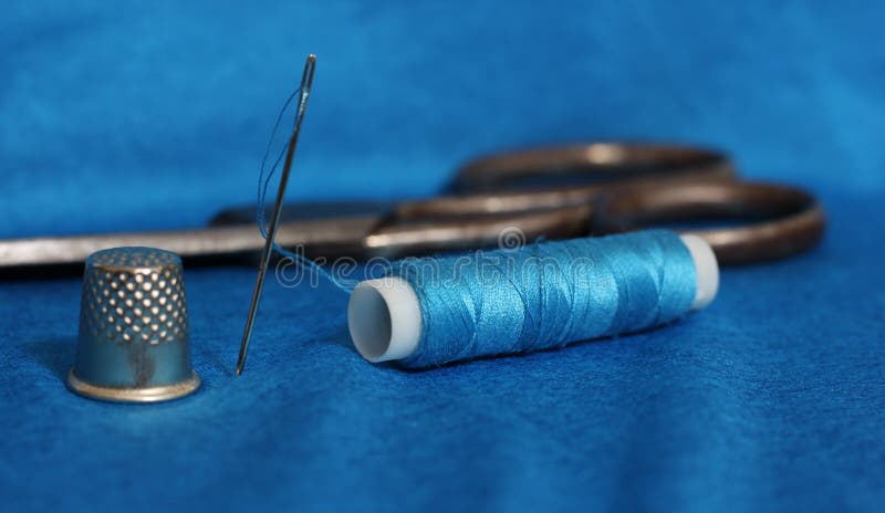 Spool of Blue Thread, Thimble and Needle on Blue Fabric Stock Image ...