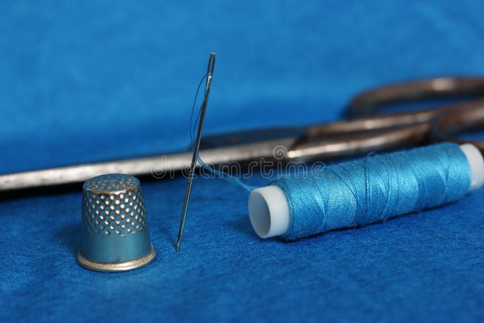 Spool of Blue Thread, Thimble and Needle on Blue Fabric Stock Image ...