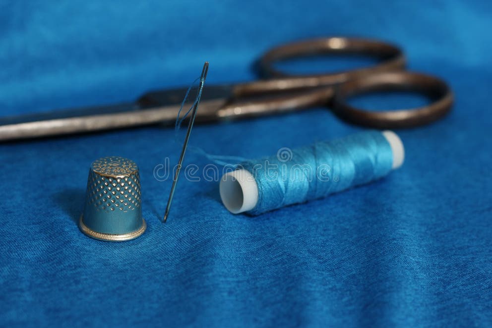 Spool of Blue Thread, Thimble and Needle on Blue Fabric Stock Image ...