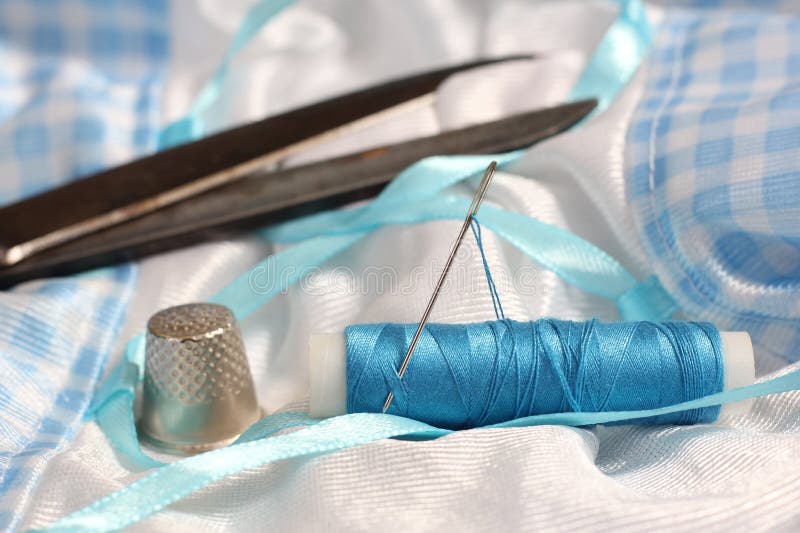 Spool of Blue Thread, Thimble and Needle on Blue and White Fabric Stock ...