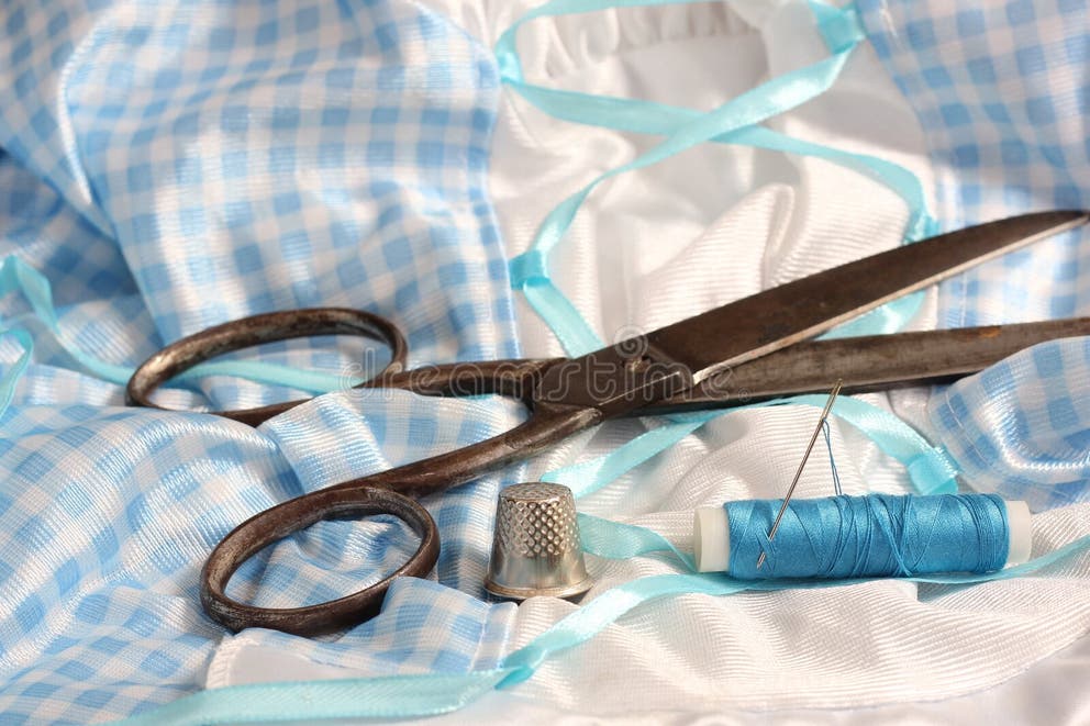 Spool of Blue Thread, Thimble and Needle on Blue and White Fabric Stock ...