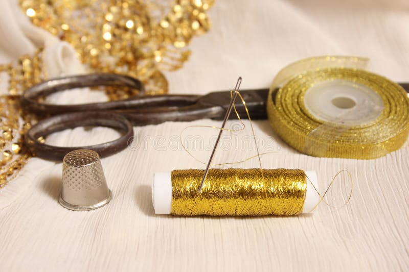 Spool of Gold Thread and Scissors with Thimble on Off White Fabric with ...
