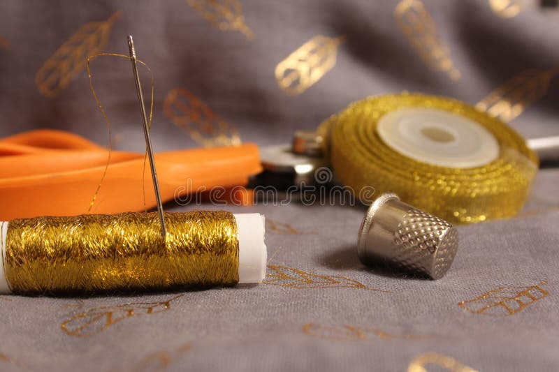 Spool of Metallic Gold Thread on Gray and Gold Chiffon Fabric Stock ...