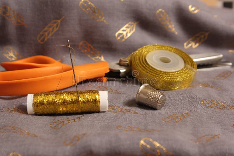 Spool of Metallic Gold Thread on Gray and Gold Chiffon Fabric Stock ...