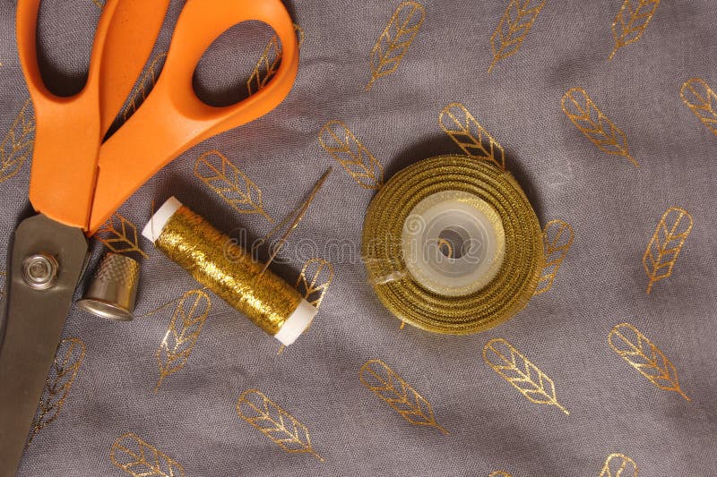 Spool of Metallic Gold Thread on Gray and Gold Chiffon Fabric Stock ...