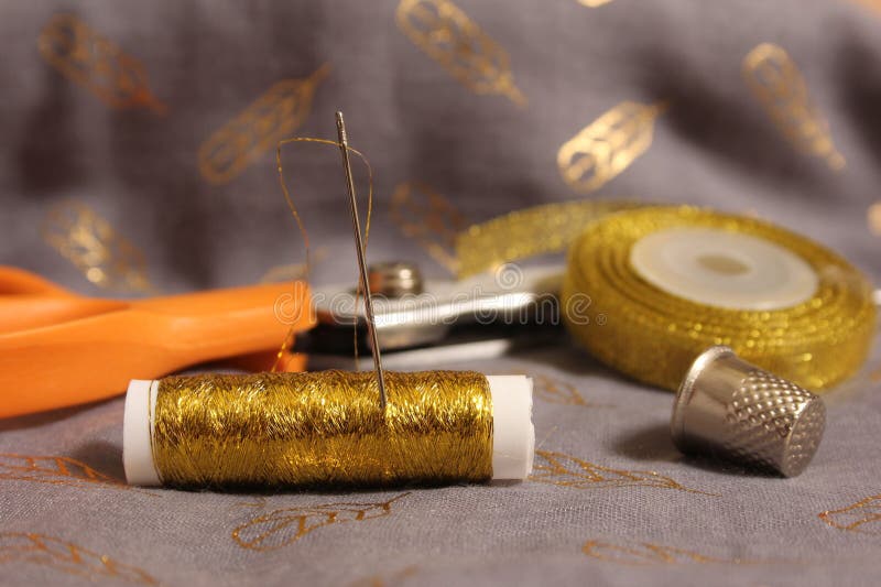 Spool of Metallic Gold Thread on Gray and Gold Chiffon Fabric Stock ...