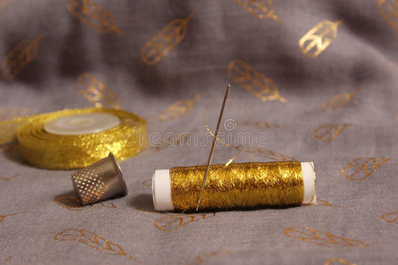 Spool of Metallic Gold Thread on Gray and Gold Fabric Stock Photo ...